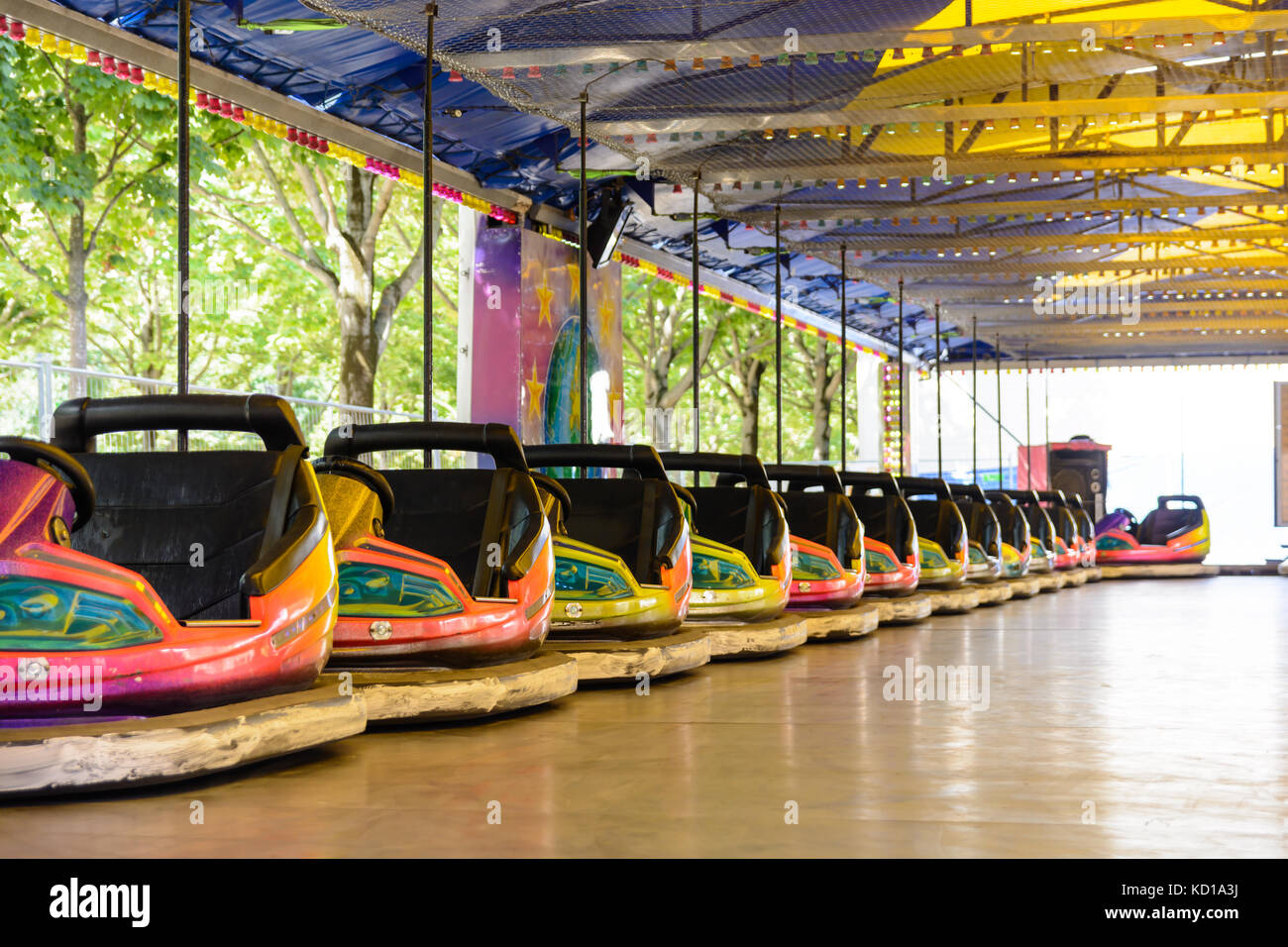 Colorful dodgem cars lined up on the side of the track waiting for kids ...
