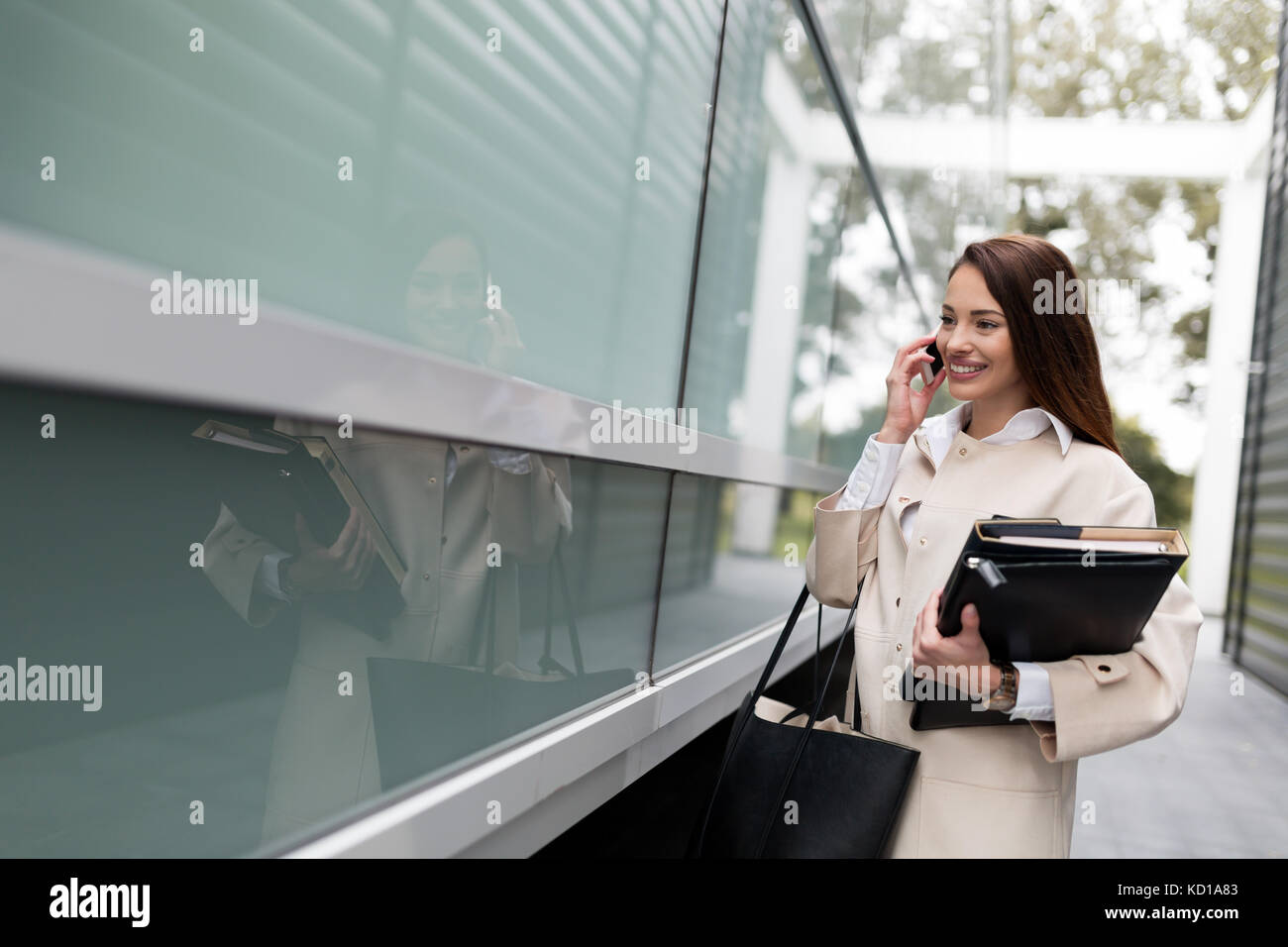 Attractive businesswoman standing and taking call Stock Photo - Alamy