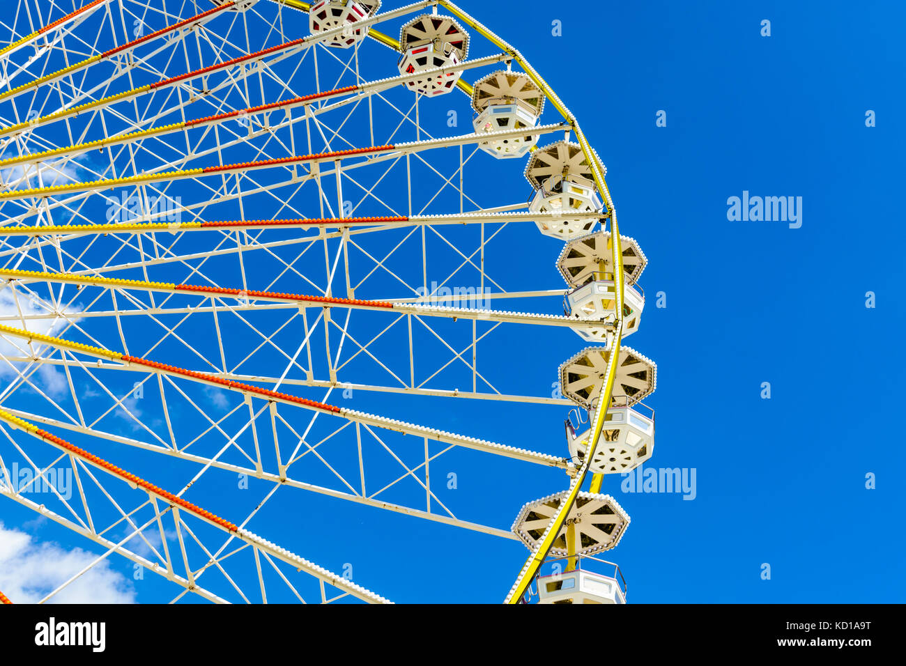 A Ferris wheel and its colorful passenger baskets against blue sky ...