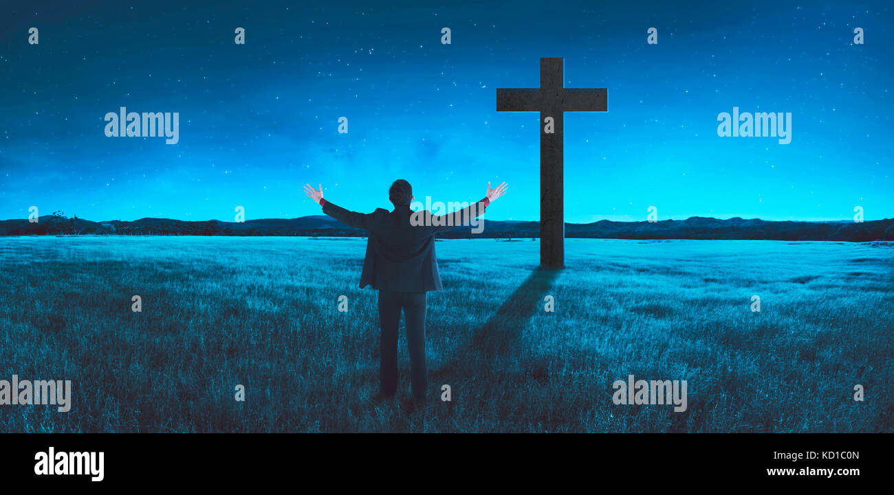 Man standing in the middle of the meadow, praying. Religion concept ...