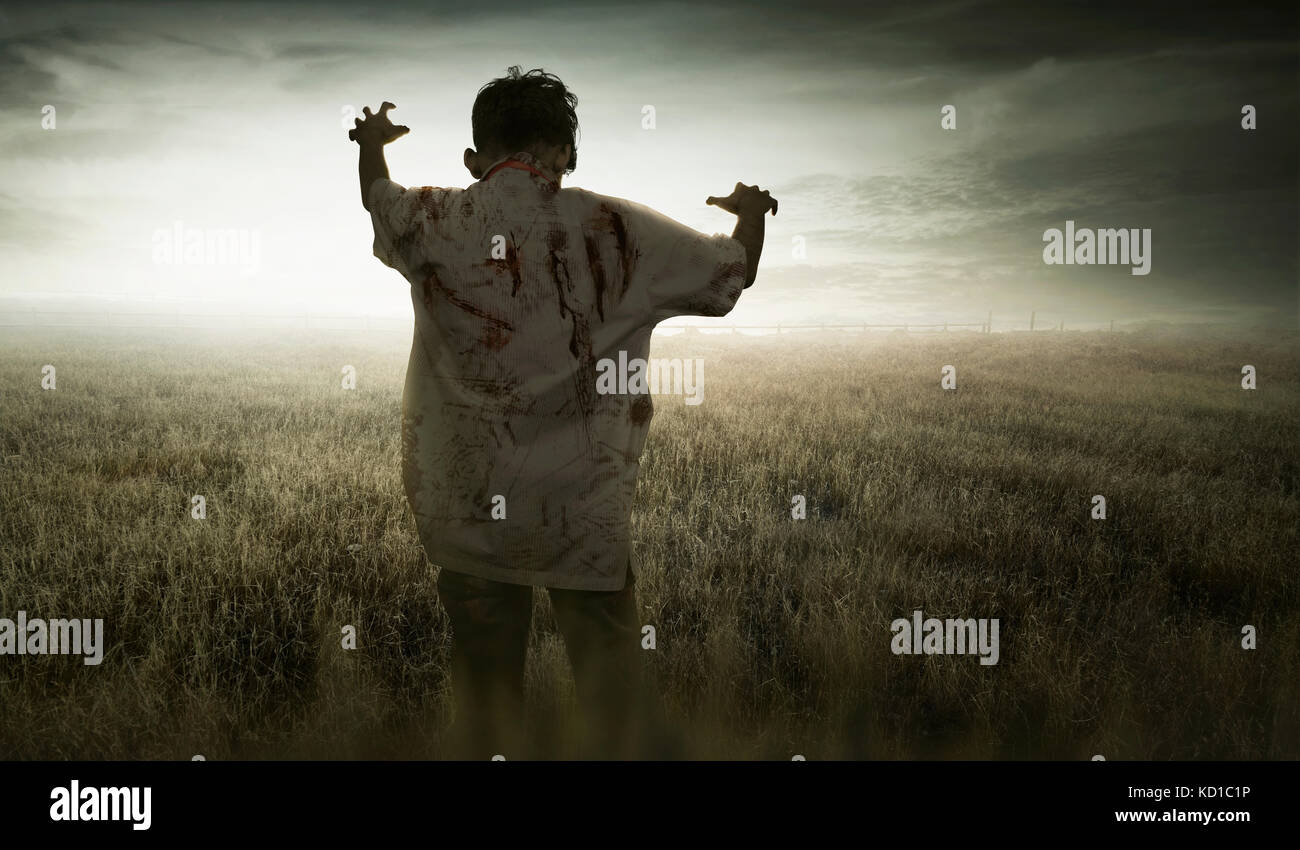 Angry asian zombie man with blood in his clothes standing on the grass ...