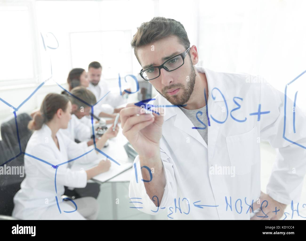 from behind the glass.scientist writes a marker on a glass Board Stock ...