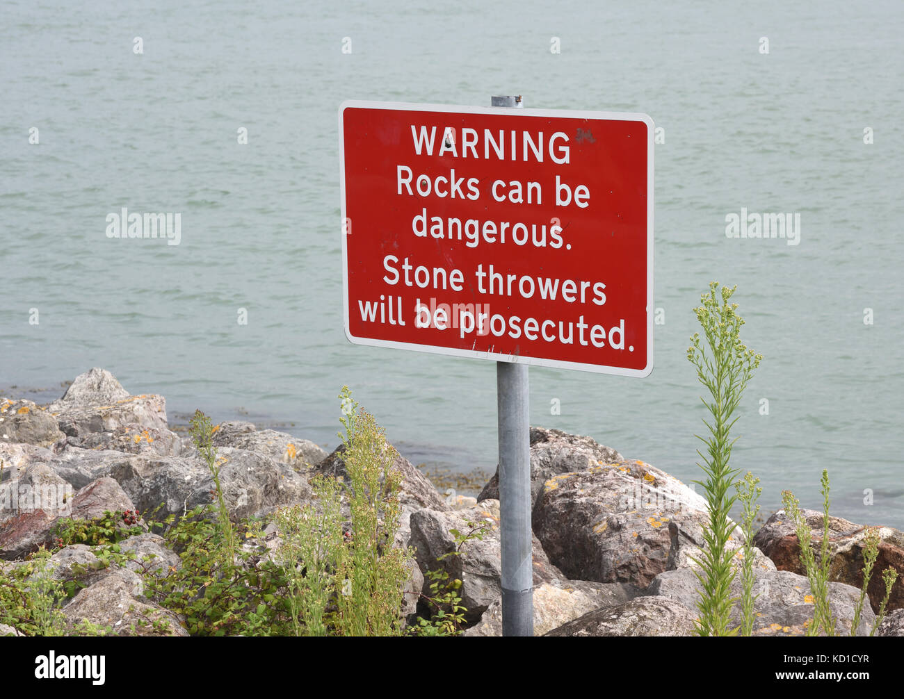 A red warning sign on rocks by the promenade at Southsea. The sign says ...