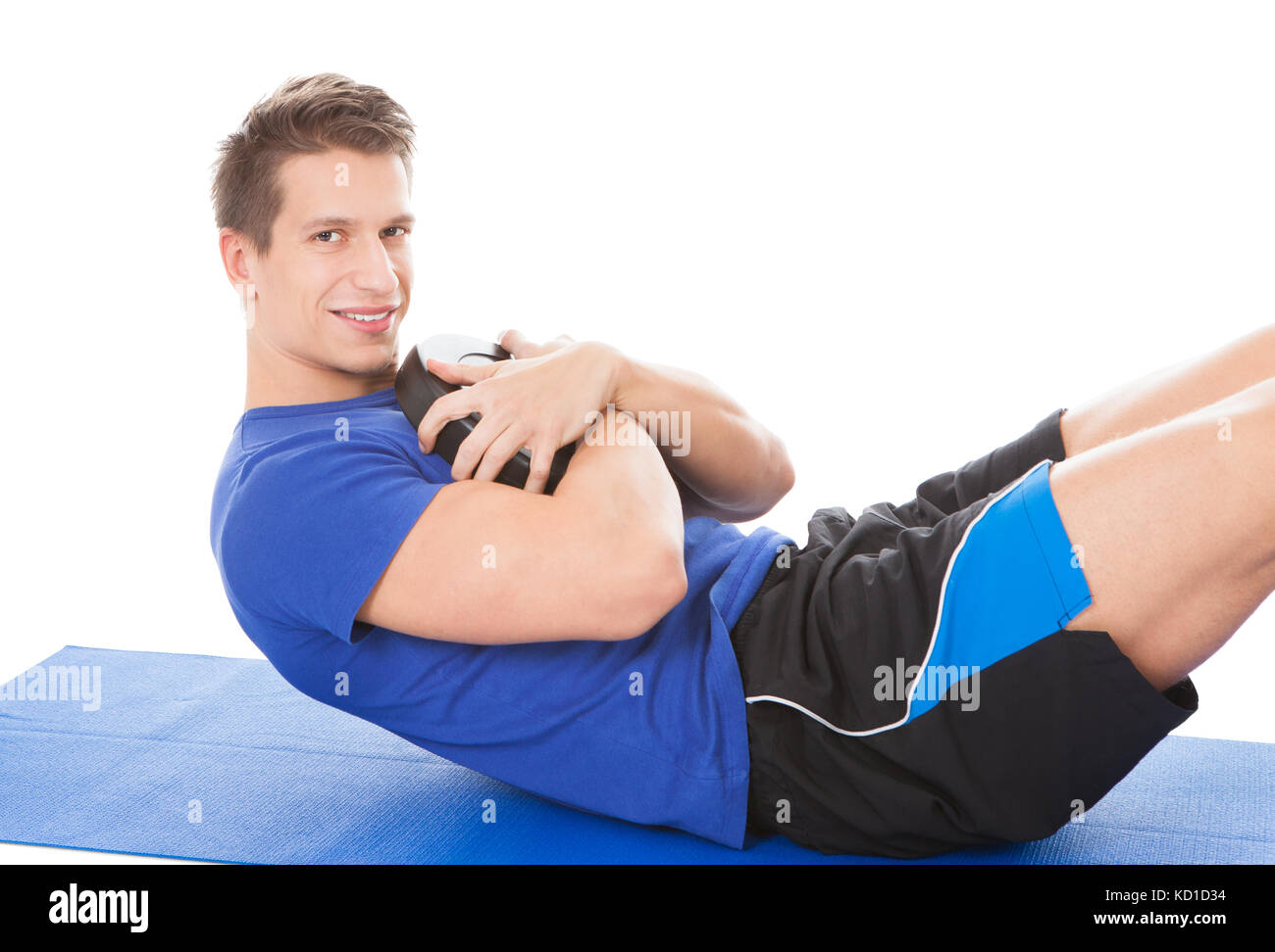 Portrait Of Young Man Holding Weight Doing Crunches Over White ...
