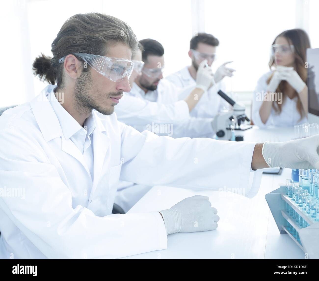Scientists working with a microscope and make notes in the workplace ...