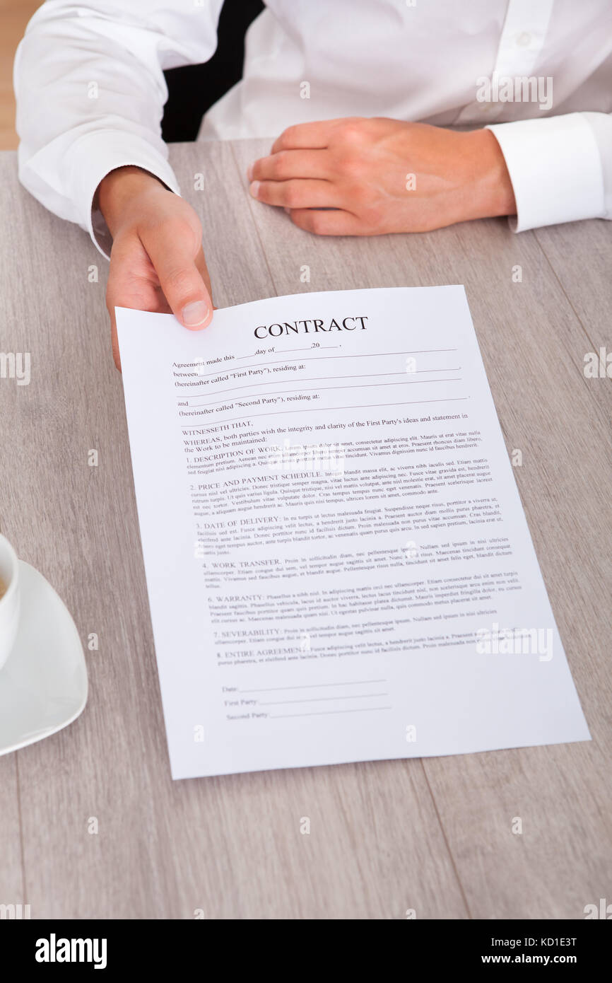 Businessman's Hand Holding Contract Paper On Desk Stock Photo - Alamy