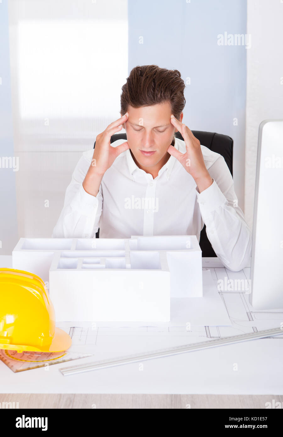 Frustrated Male Architect Sitting In Front Of Architectural Model In ...