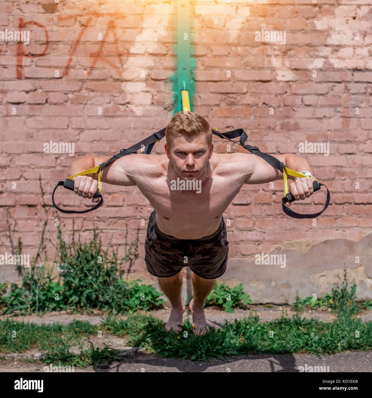 A male athlete is engaged in open air loops, trains chest, pushing away ...