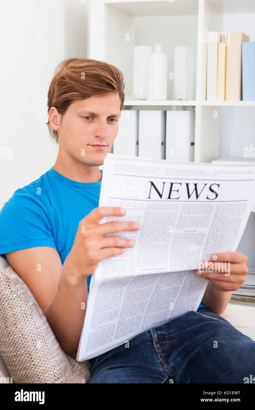 Young Man Sitting On Sofa And Reading Newspaper Stock Photo - Alamy