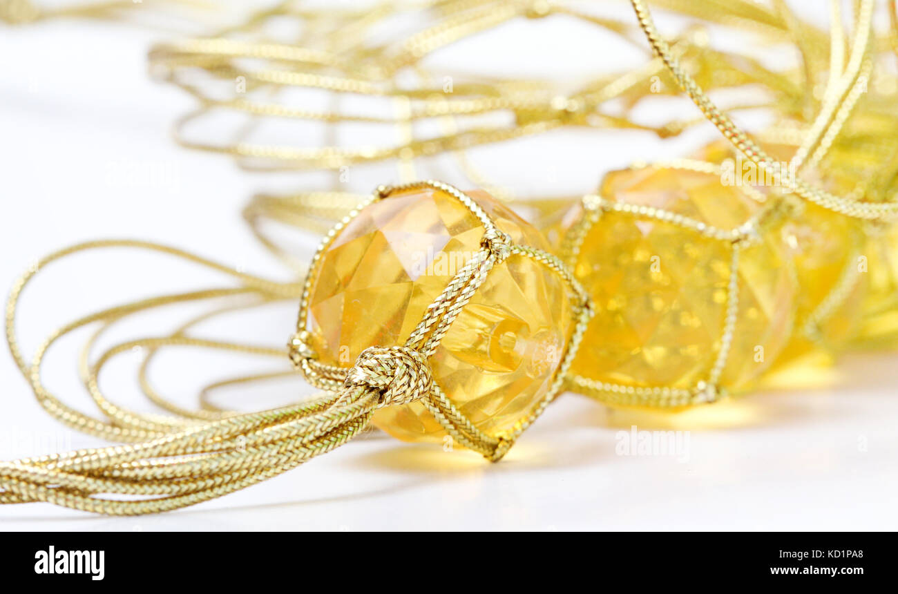 picture of a necklace with cheap plastic gems with golden colored rope ...