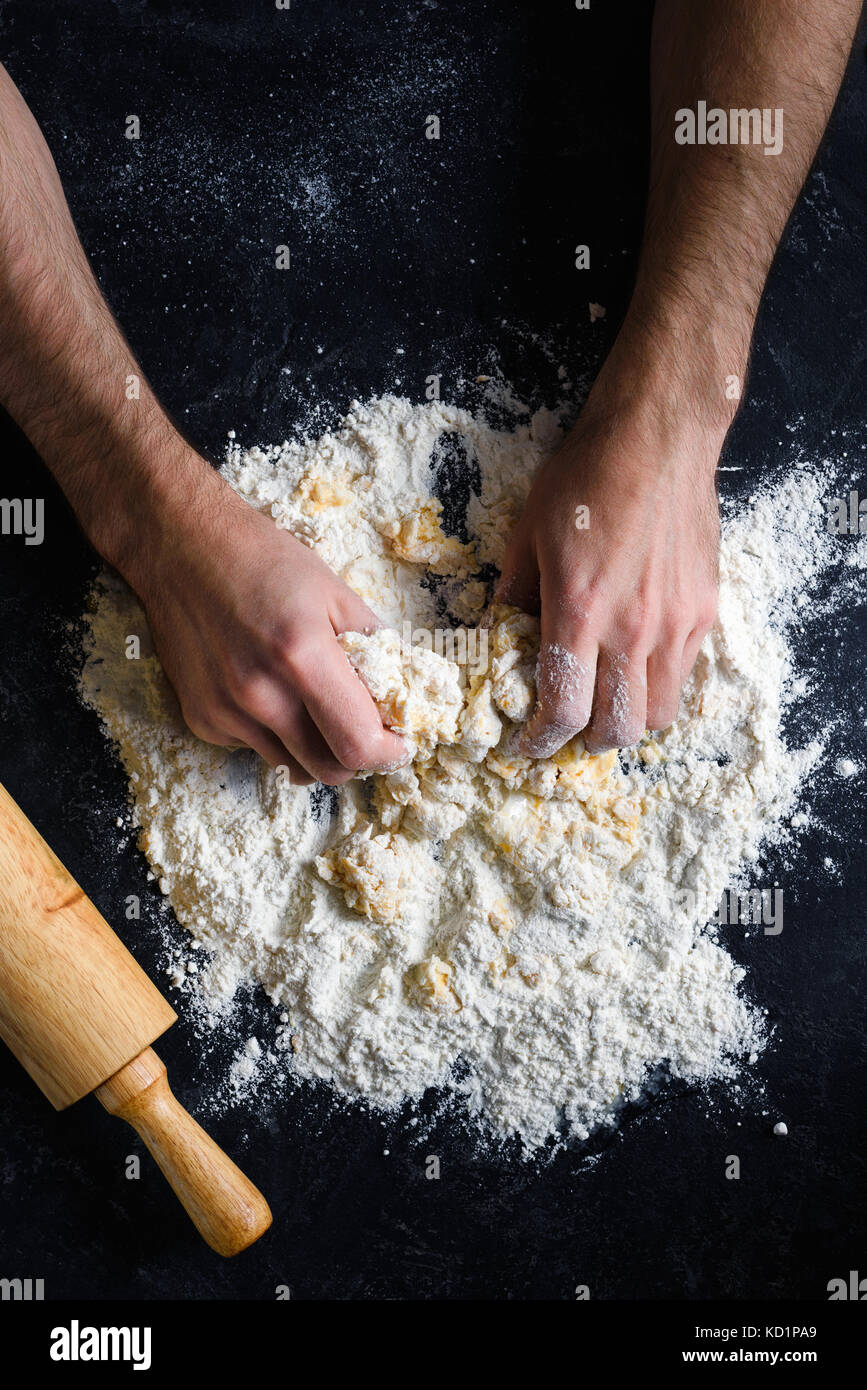 Chef making pasta dough. Man hands kneading dough on dark background ...