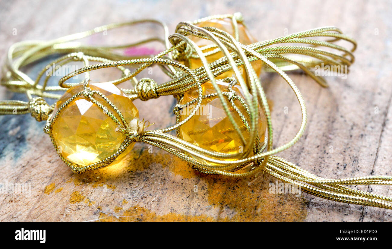 picture of a necklace with cheap plastic gems with golden colored rope ...