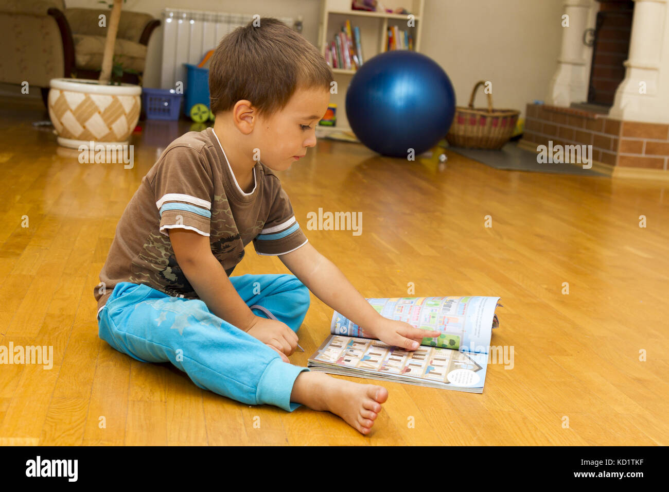 Little boy is sitting on the floor with a book Stock Photo - Alamy