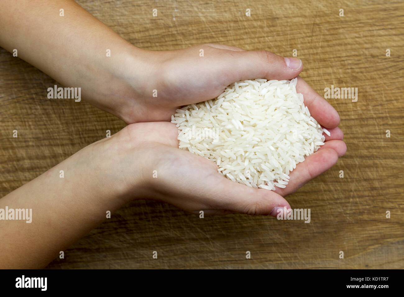 Woman hands holding pile of white raw rice, which is traditional food ...