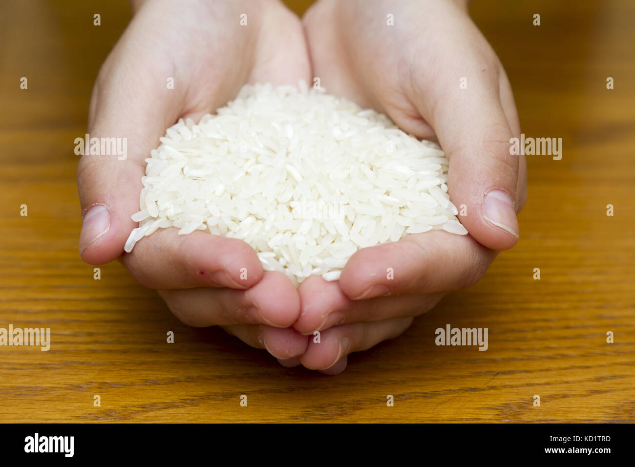 Woman hands holding pile of white raw rice, which is traditional food ...