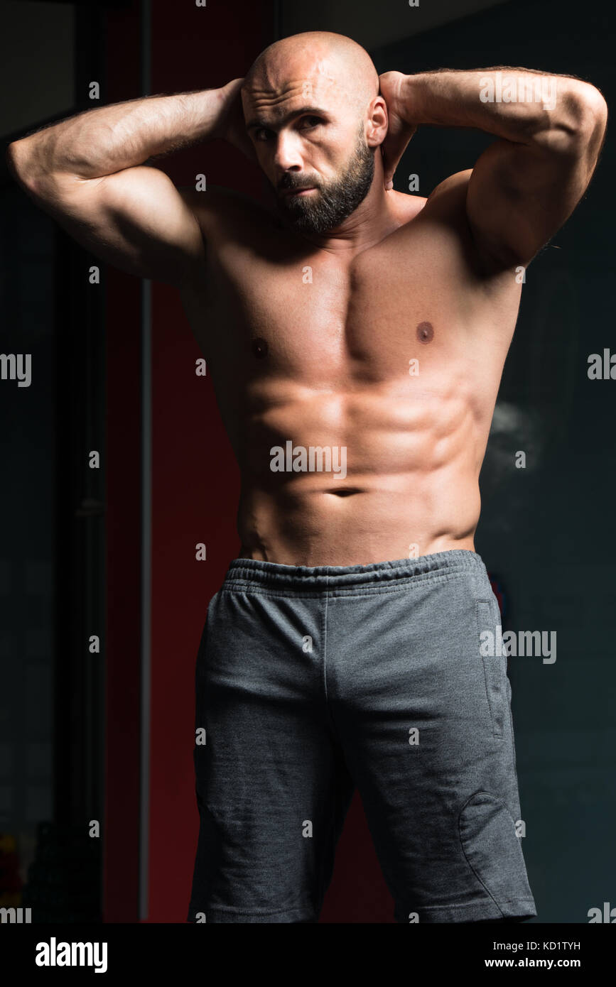 Handsome Young Man Standing Strong In The Gym And Flexing Muscles ...