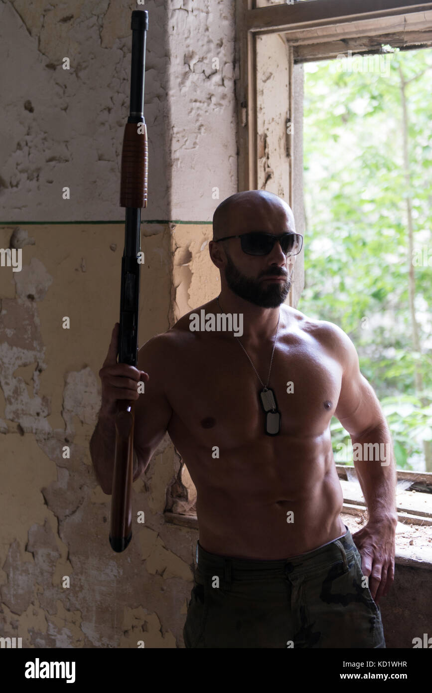 Action Hero Muscled Man Holding Machine Gun - Standing In Abandoned ...