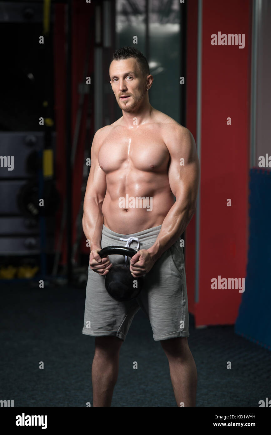 Young Man Exercising With Kettle Bell And Flexing Muscles - Muscular ...
