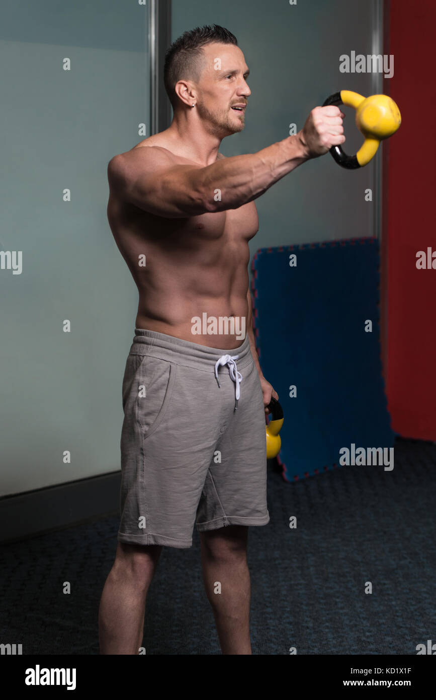 Young Man Working Out With Kettle Bell In A Dark Gym - Bodybuilder ...