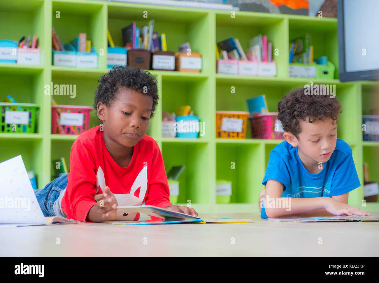 Two boy kid lay down on floor and reading tale book in preschool ...