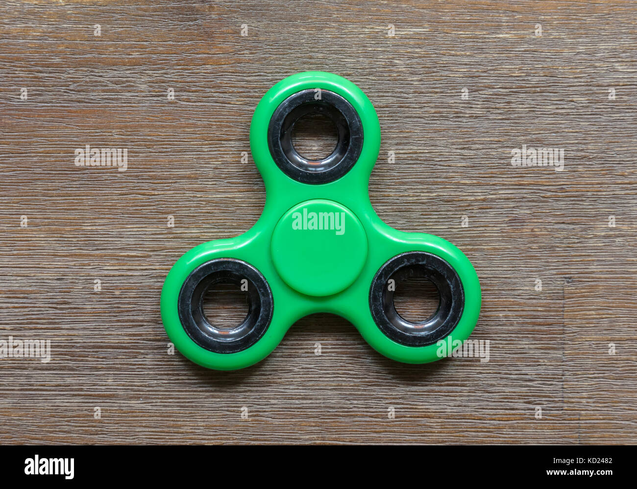 Image of Fidget finger spinner stress toy - Green spinner on a wooden ...