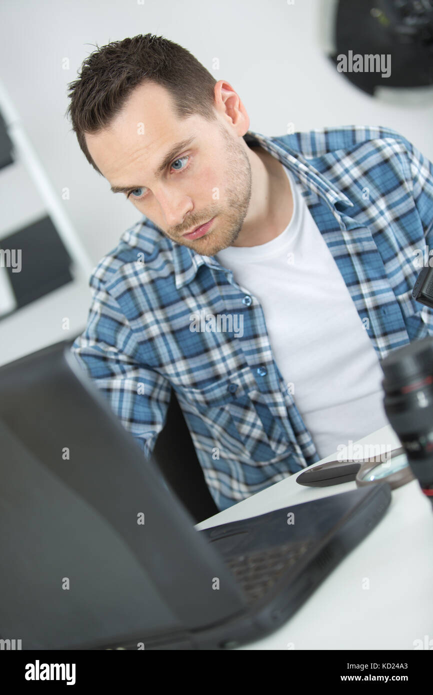 photographer checking photos in camera at desk in office Stock Photo ...