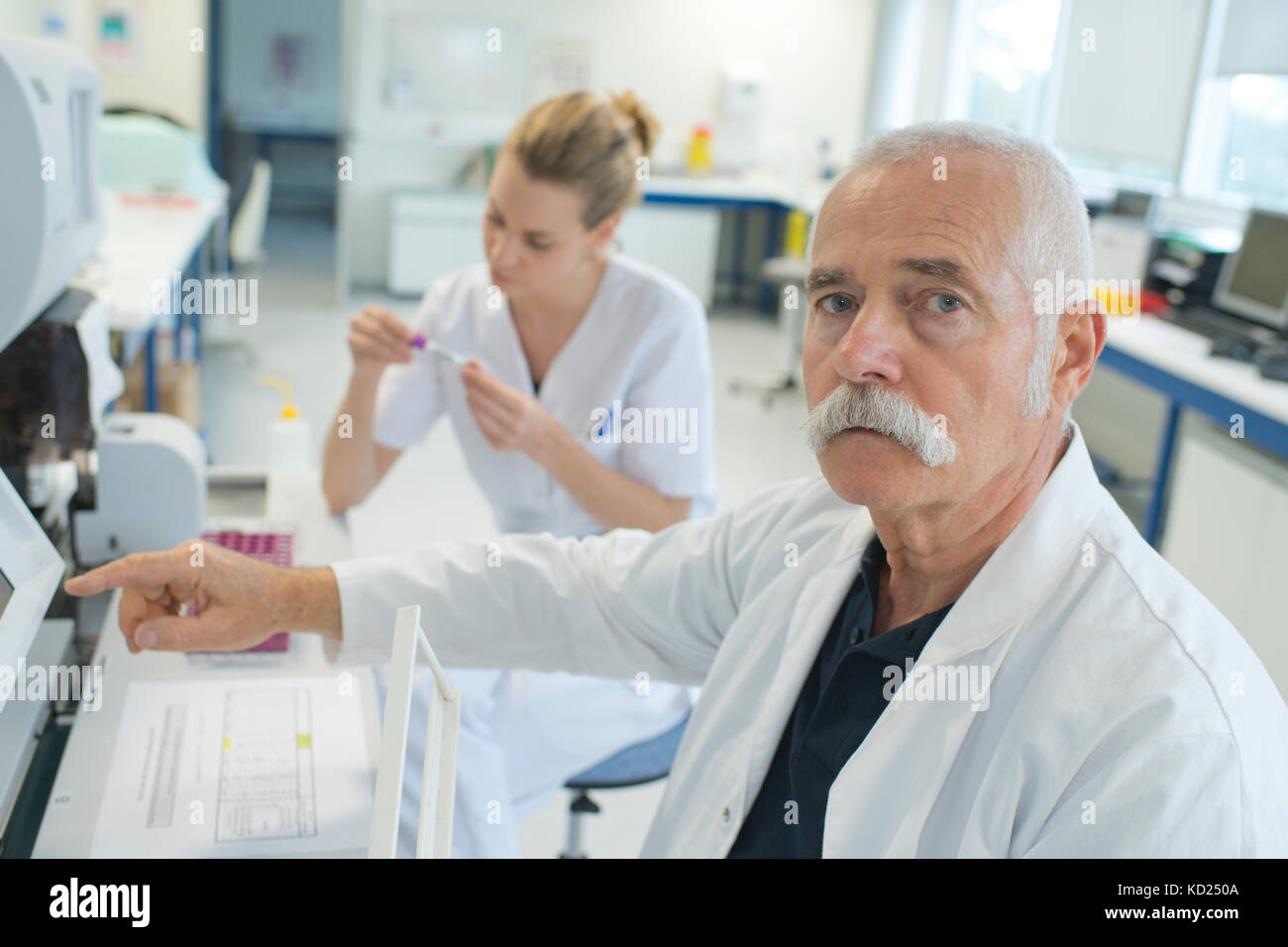 Senior lab worker pointing to computer screen Stock Photo - Alamy