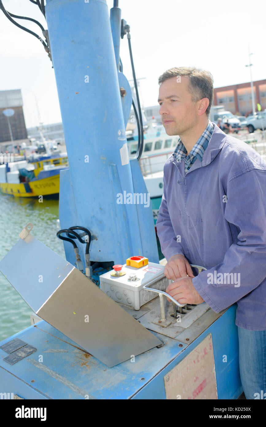 Man operating crane in estuary Stock Photo - Alamy