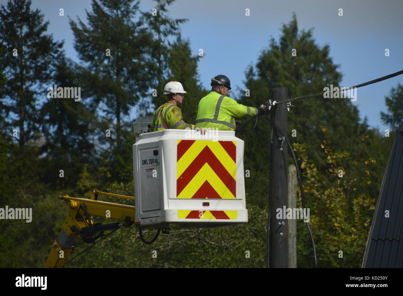 Power company workers working on overhead power lines from cherry ...