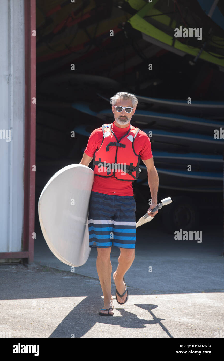 man holding stand up paddle board walking towards the water Stock Photo ...