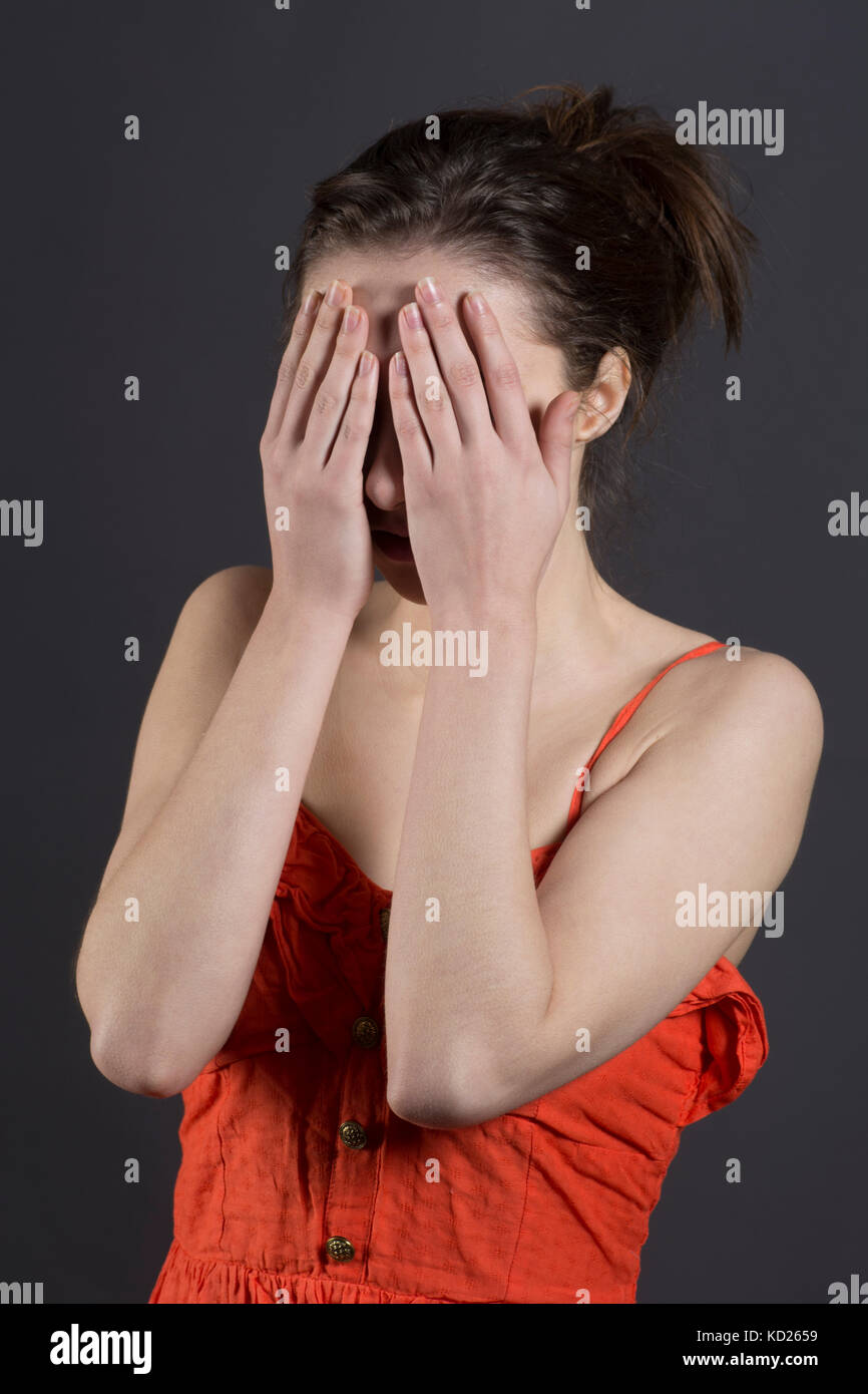 Young woman hiding face with hands Stock Photo - Alamy