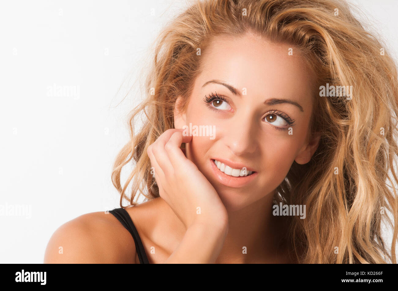 Beautiful young woman hand touching face looking up smiling against a ...