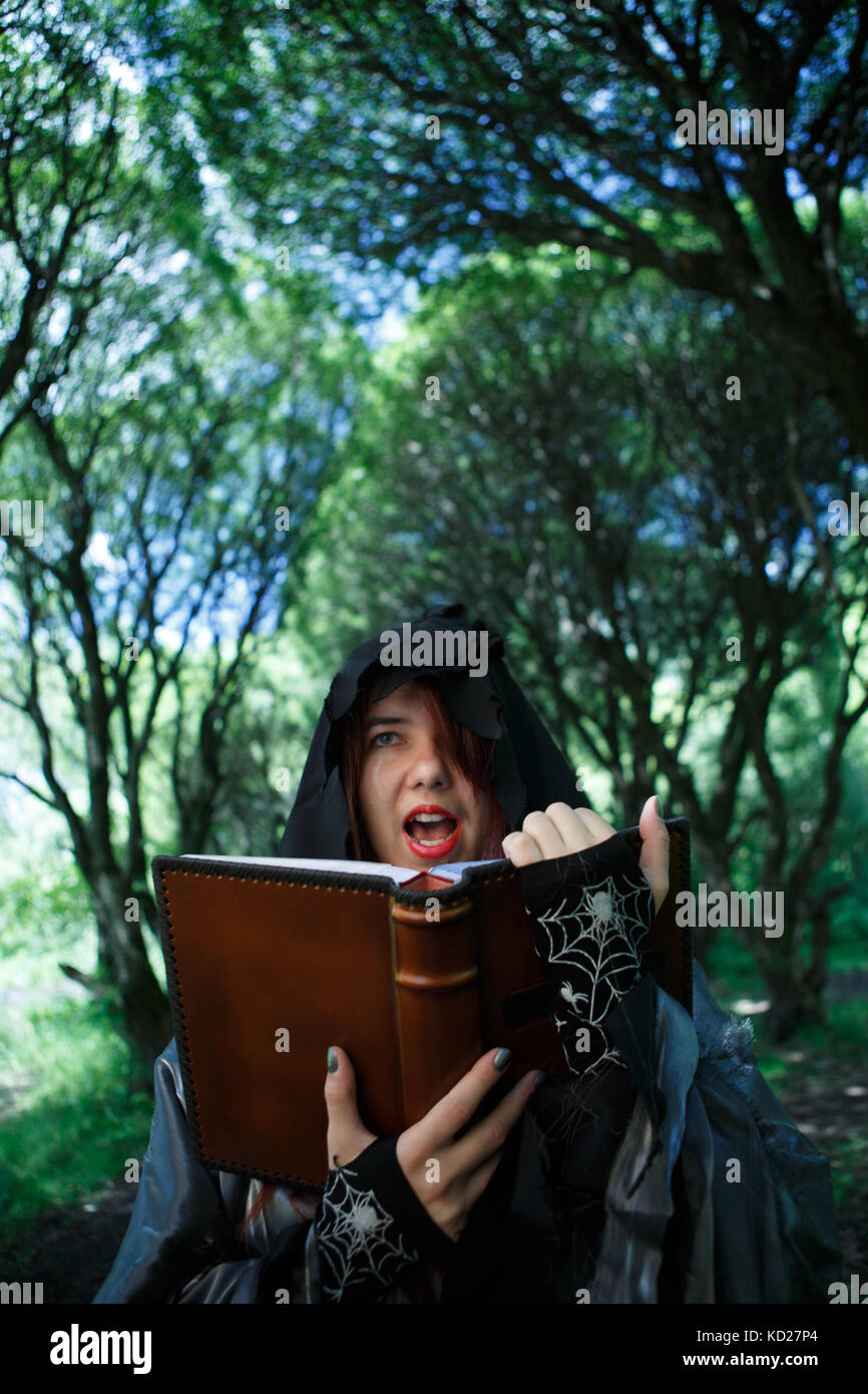 Witch reading spell from book Stock Photo - Alamy