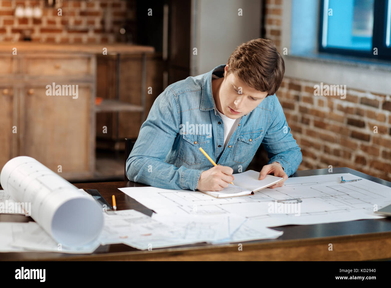 Young engineer making notes regarding his project Stock Photo - Alamy