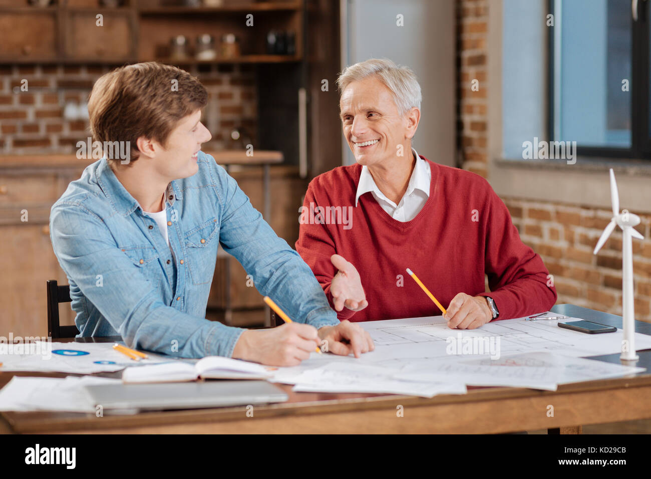 Senior colleague discussing project with young colleague Stock Photo ...