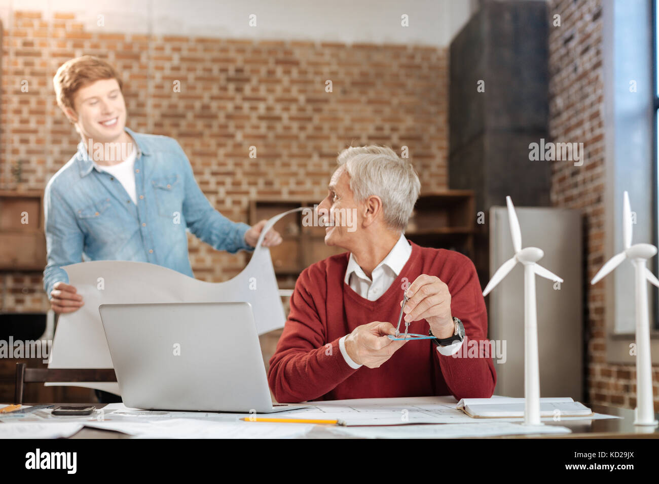 Pleasant engineers communicating while working on blueprints Stock ...