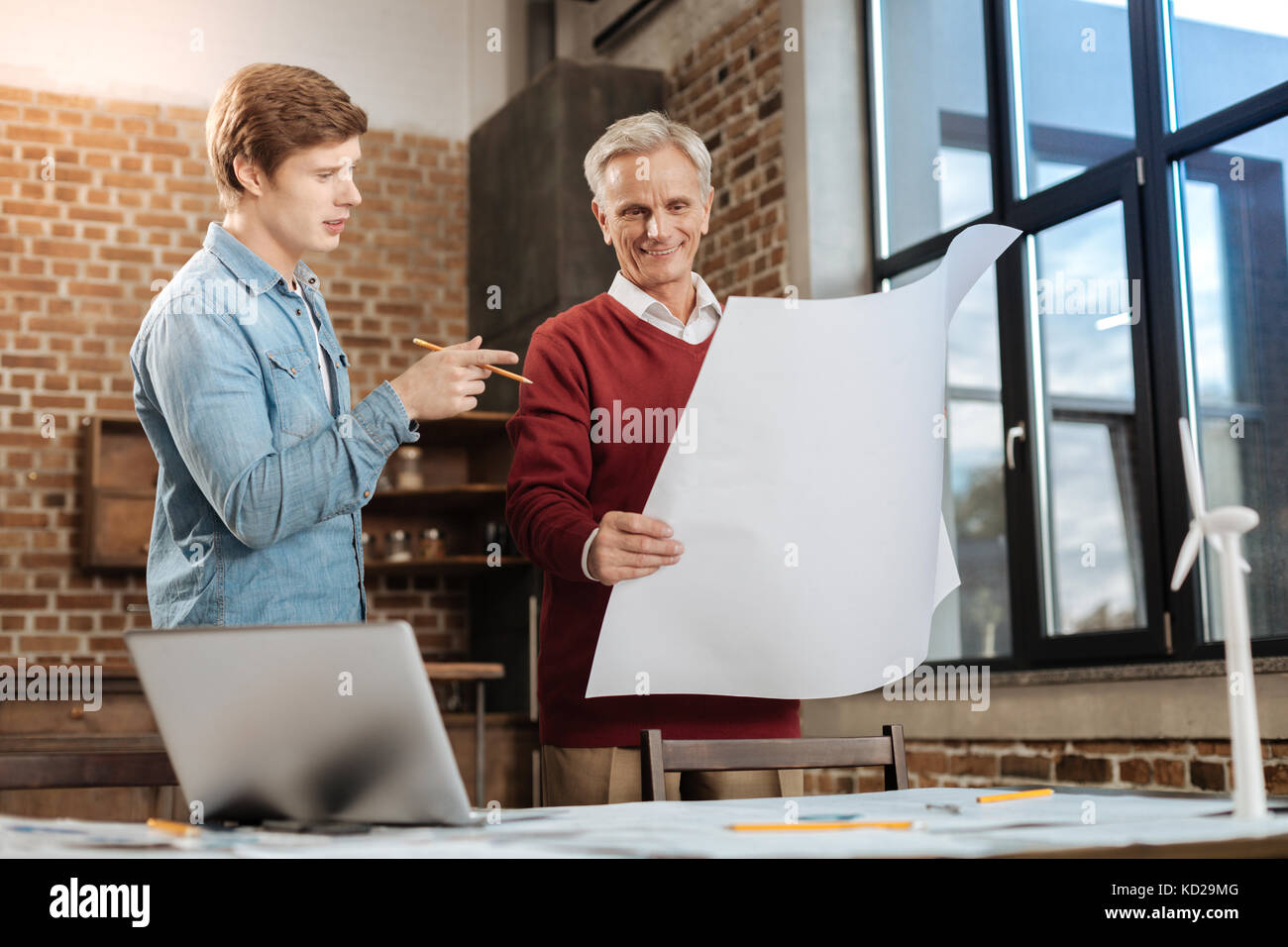 Young engineer asking senior colleague questions about blueprint Stock ...