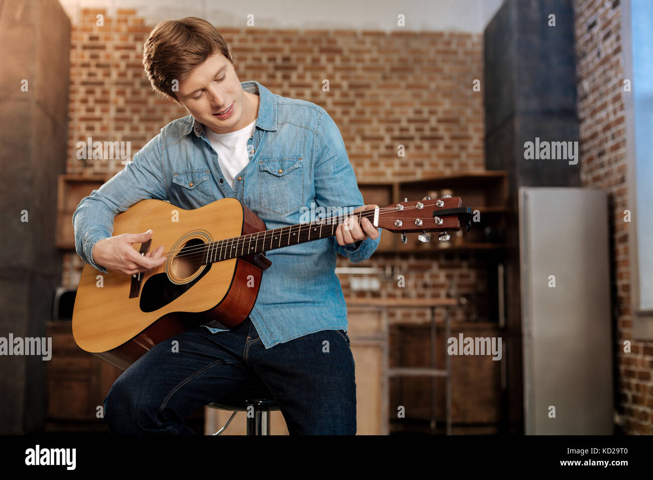 Pleasant young man playing guitar Stock Photo - Alamy