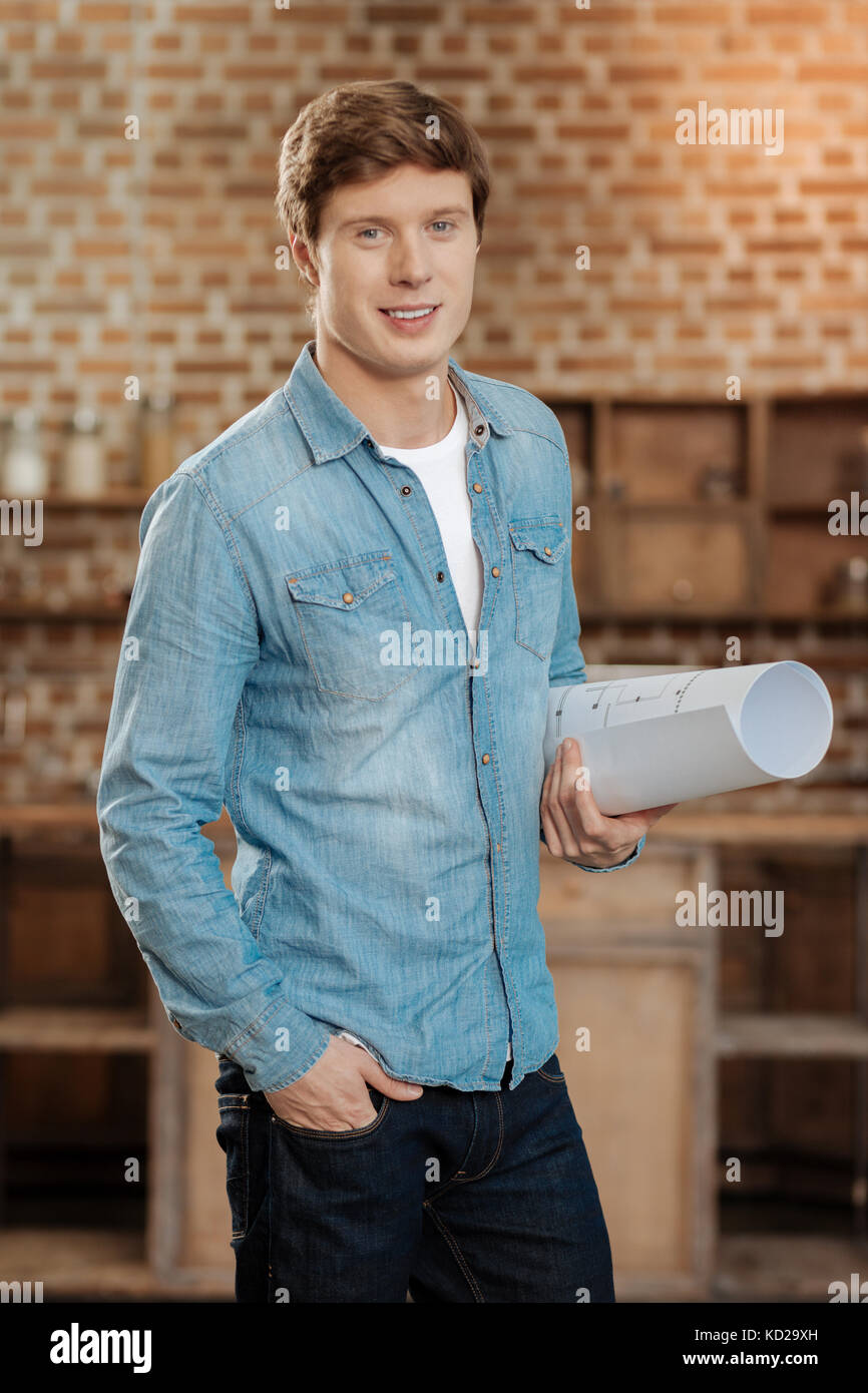 Pleasant smiling engineer posing with a rolled blueprint Stock Photo ...