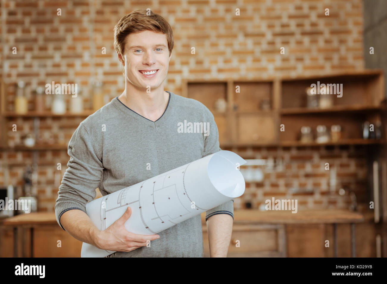 Handsome young engineer holding a rolled blueprint Stock Photo - Alamy