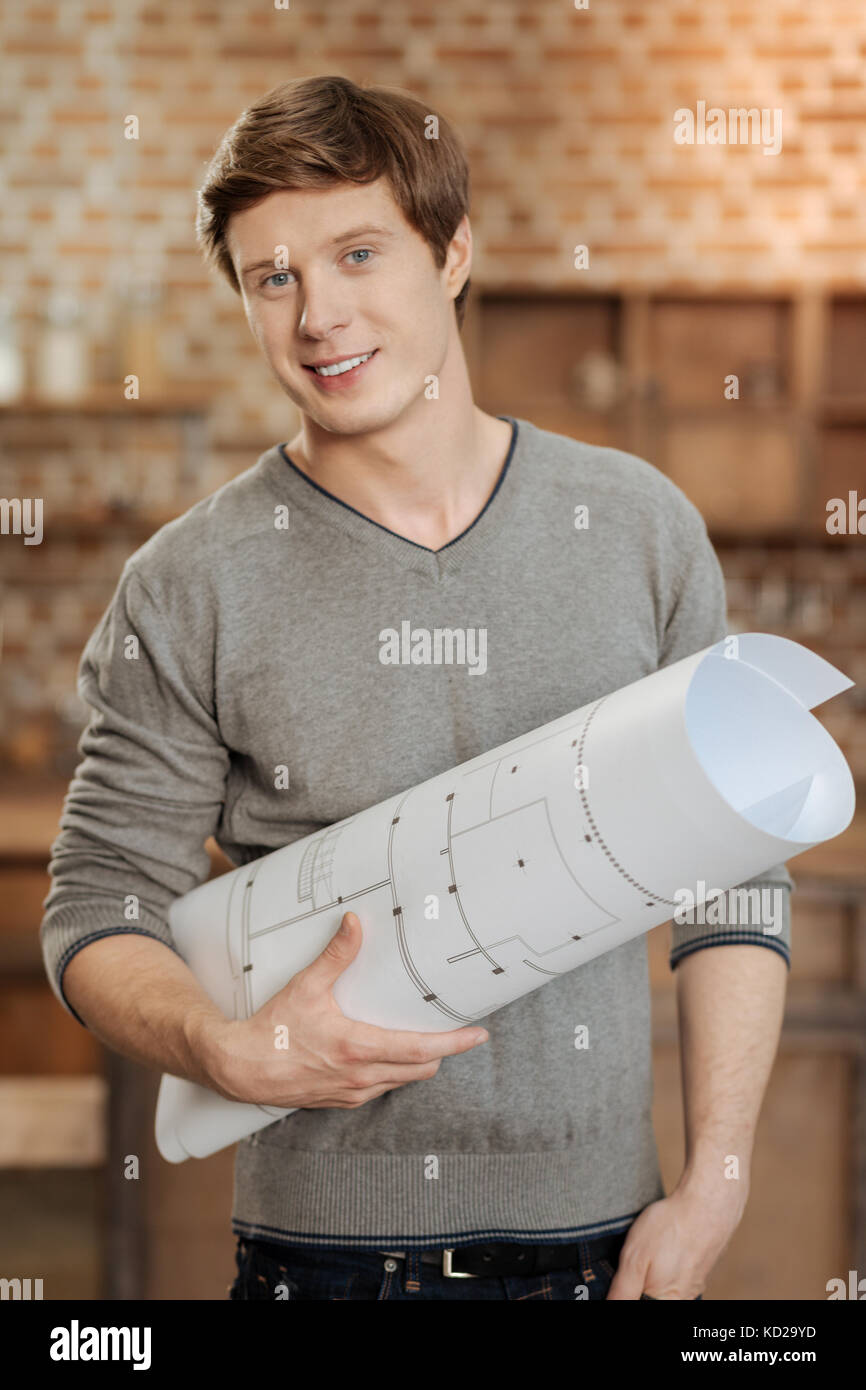 Cheerful man holding blueprint and smiling Stock Photo - Alamy