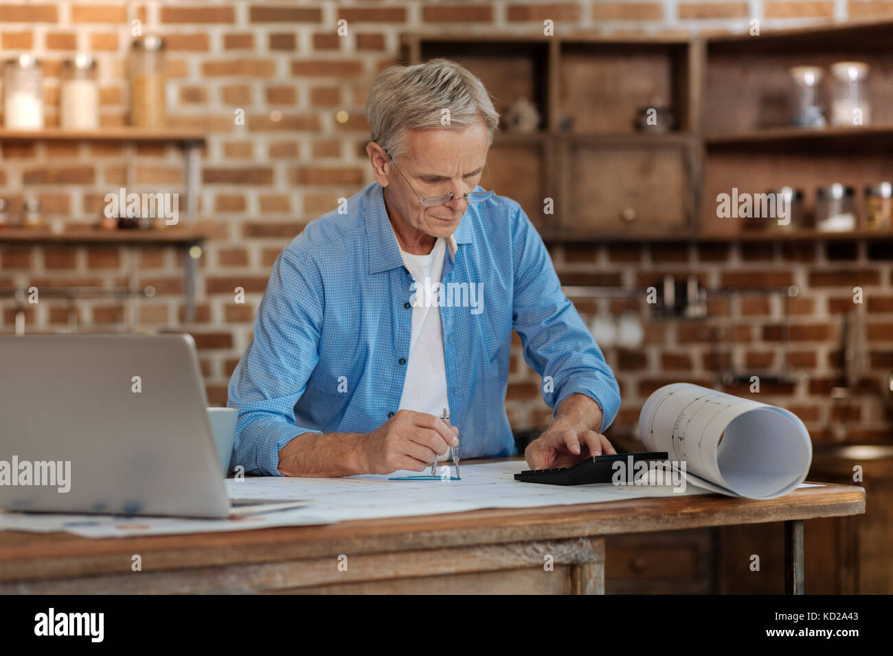 Senior man doing calculations while drawing blueprint Stock Photo - Alamy