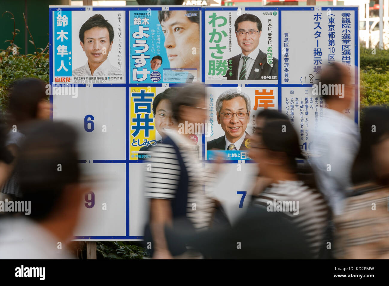 Tokyo, Japan. 10th Oct, 2017. Pedestrians walk past a poster board ...