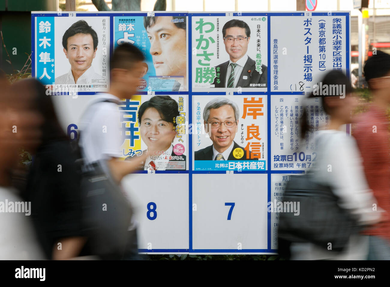 Tokyo, Japan. 10th Oct, 2017. Pedestrians walk past a poster board ...