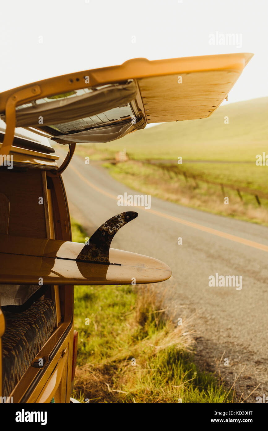 Yellow surfboard in vintage recreational vehicle boot on roadside ...