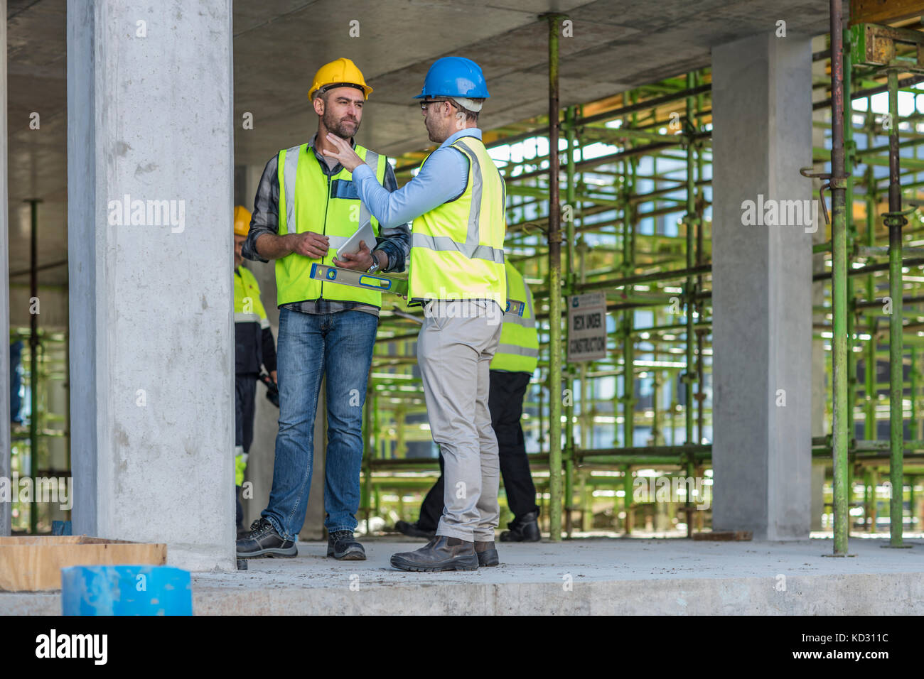 Construction workers in discussion on building site Stock Photo - Alamy