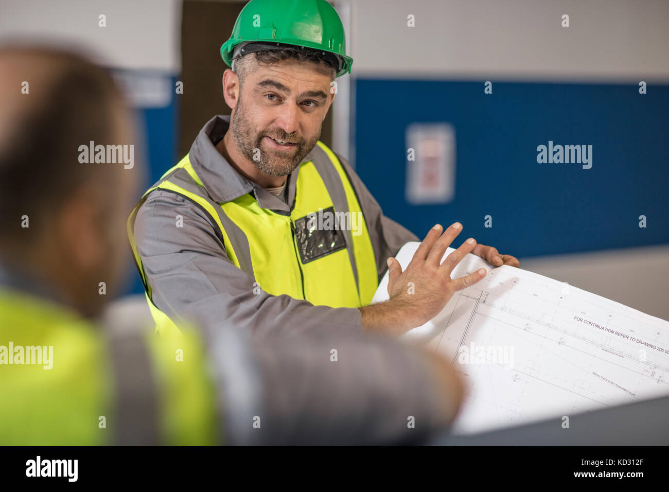 Construction workers in discussion on building site Stock Photo - Alamy