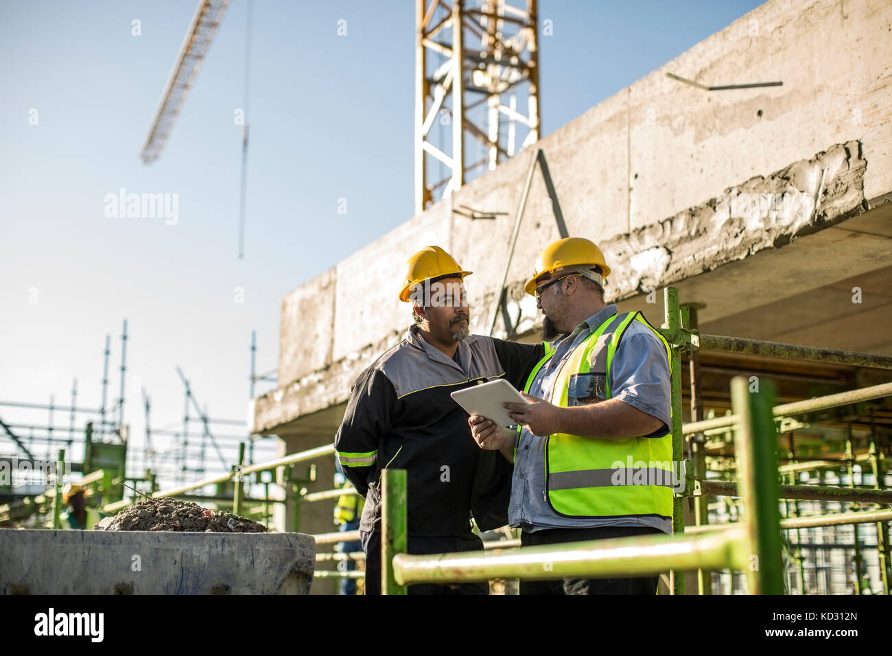 Construction workers in discussion on building site Stock Photo - Alamy