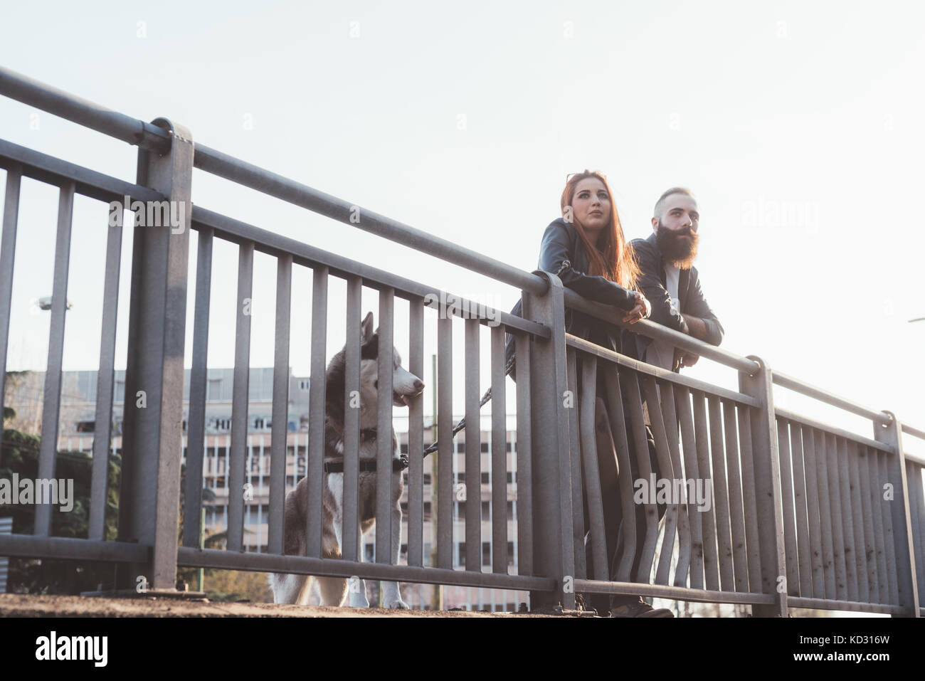 Couple leaning against railings looking away Stock Photo - Alamy