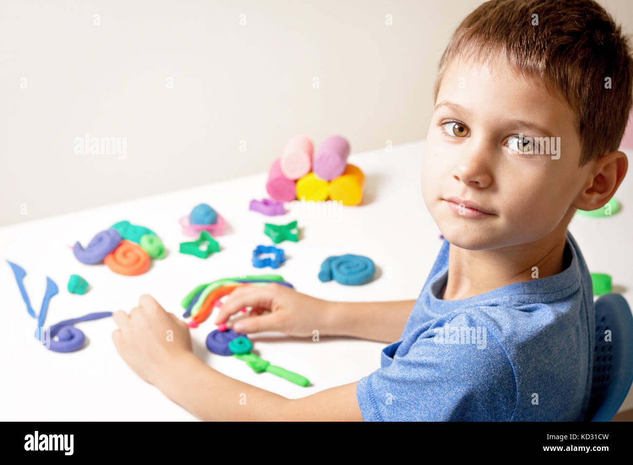 Boy playing and creating from modeling clay or plasticine on white ...